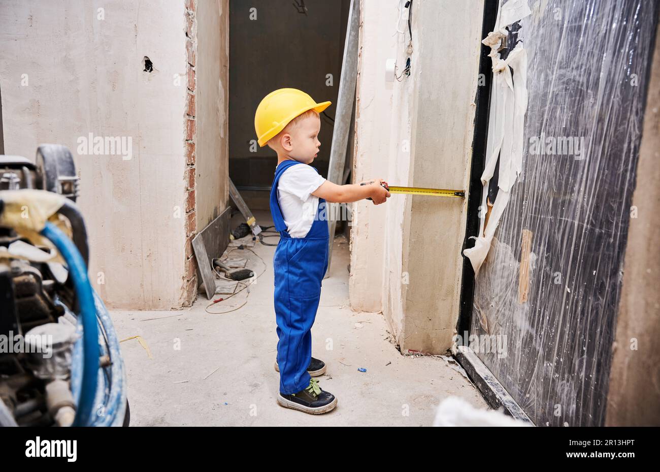 Full length of child construction worker using measuring tape in ...