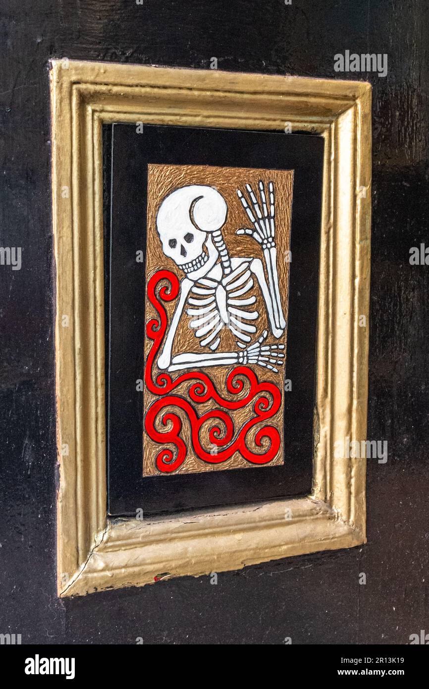 Gold gilt and red engraved sign showing a skeleton on the outside of ...
