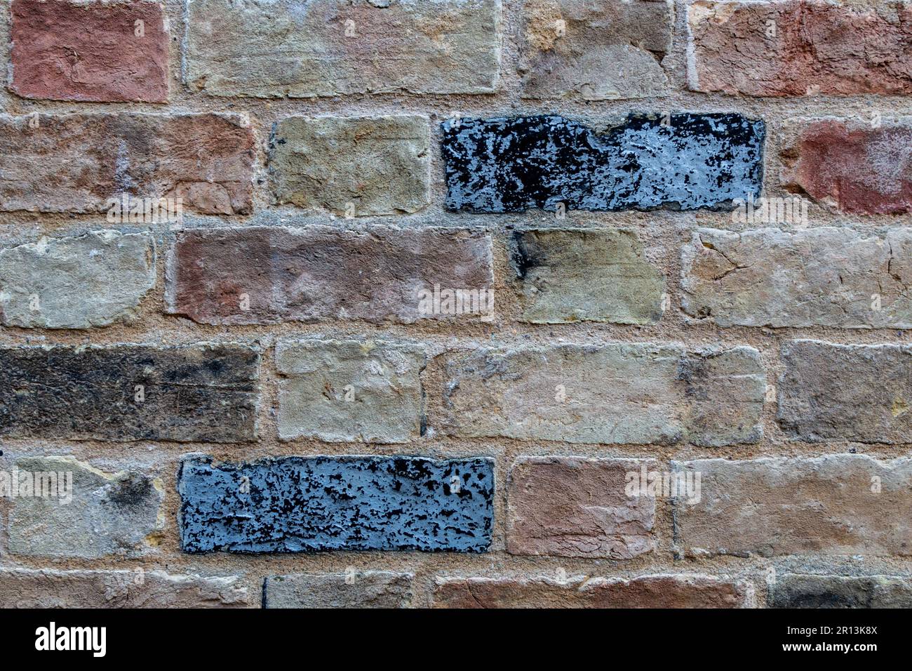 A section of yellow, red and black bricks in a wall Stock Photo - Alamy