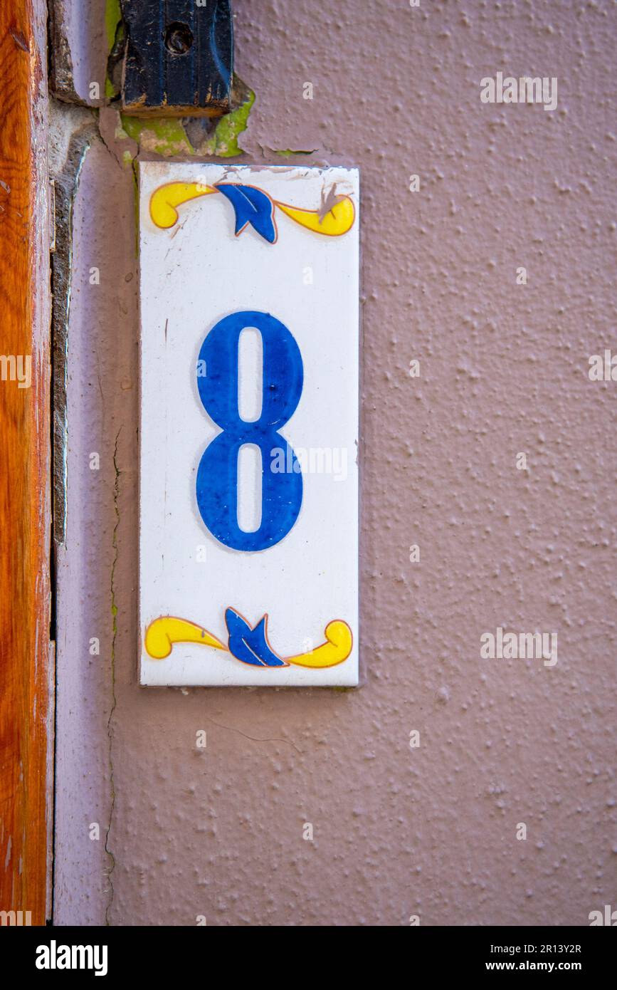 A sign with the number 8 in blue on a pink wall. The concept of ...