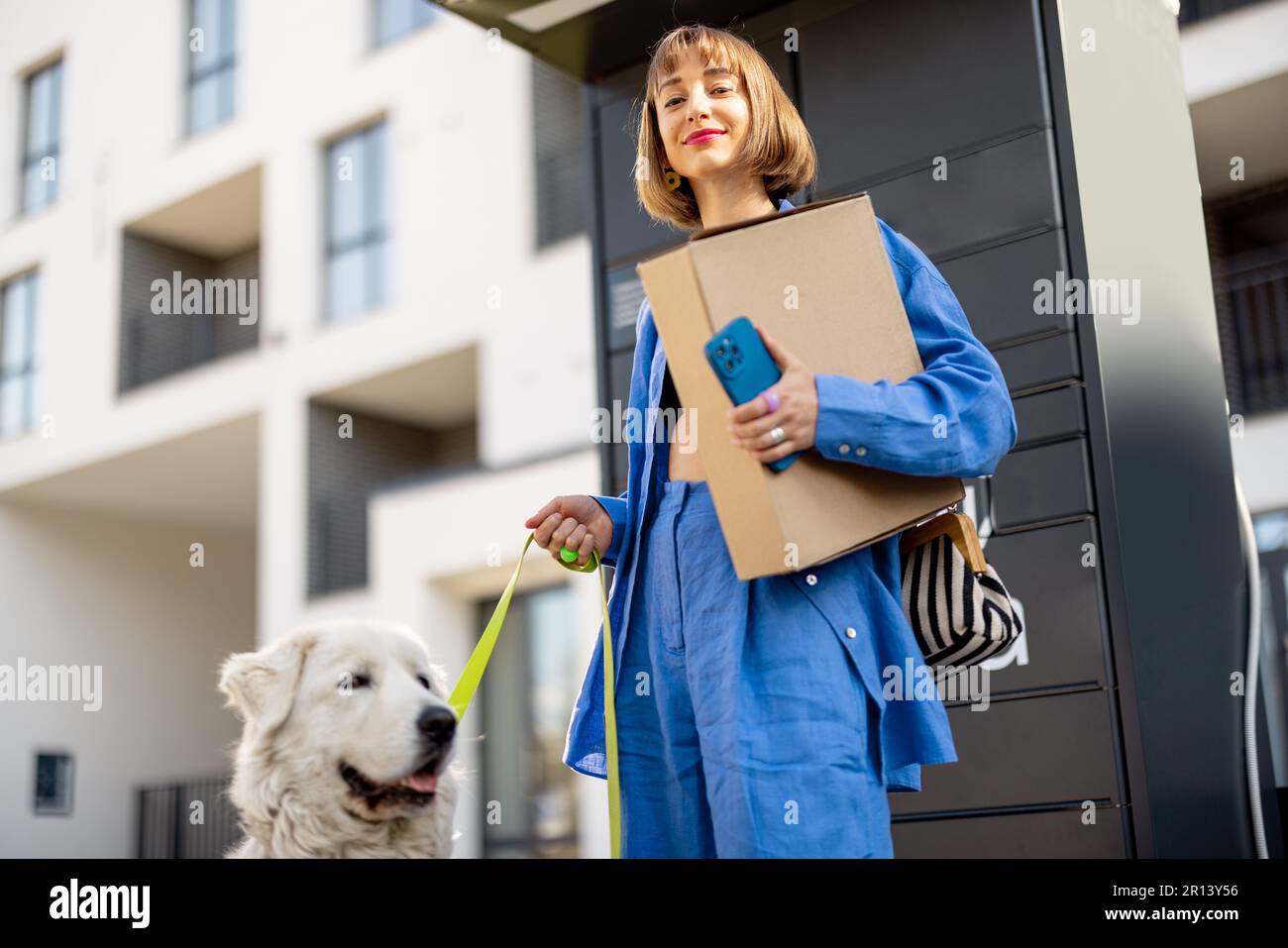 Woman with her dog picks up parcels from automatic post office machine ...