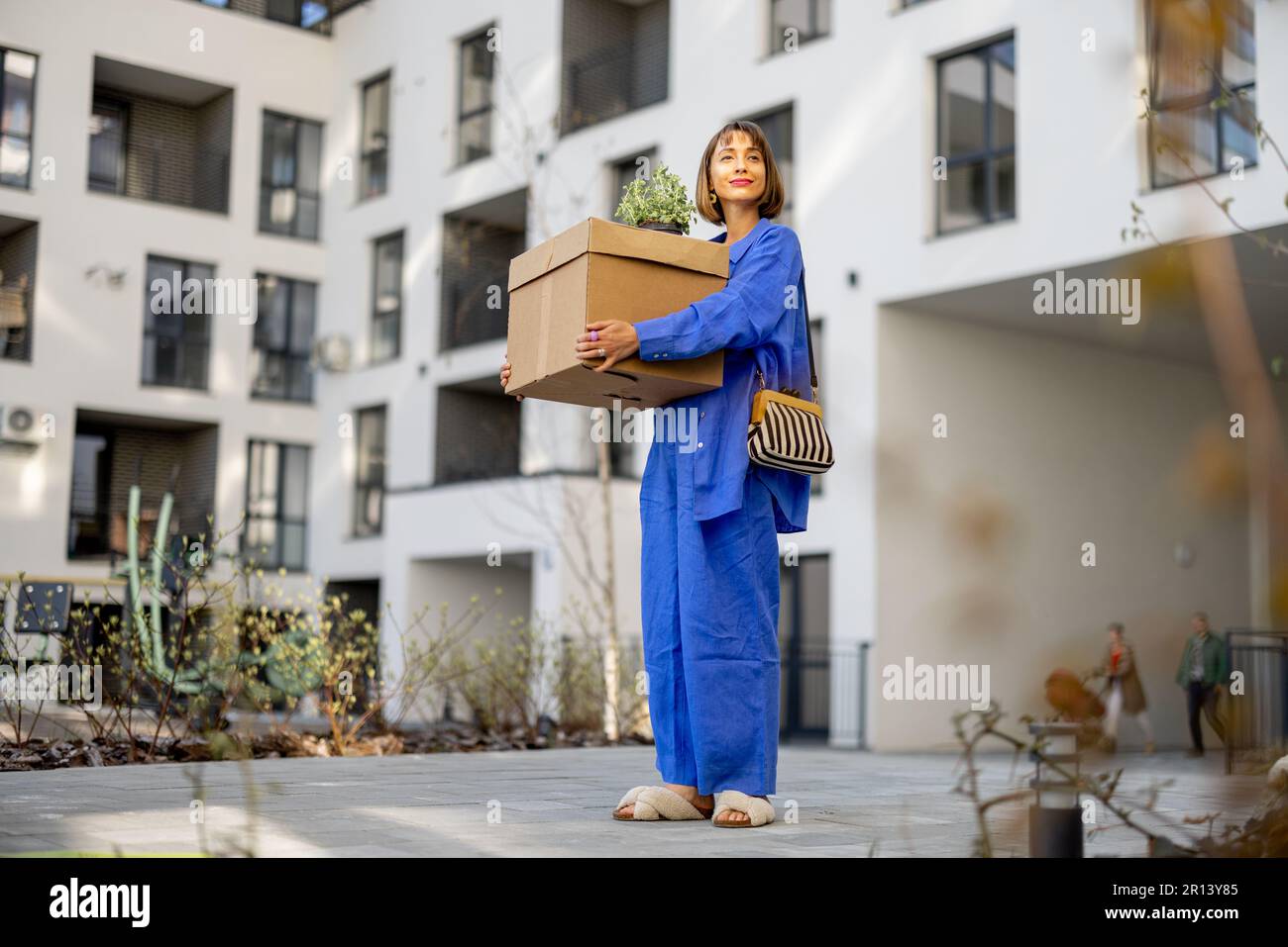 Woman carrying cardboard box at inner yard of apartment building Stock ...