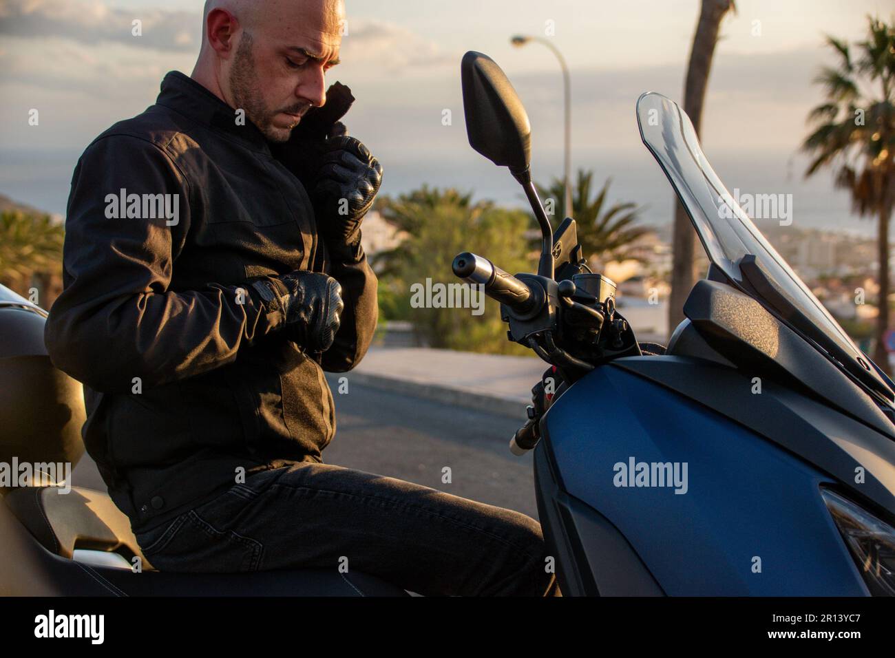 Bald caucasian biker is fastening his jacket with protectors, getting ...