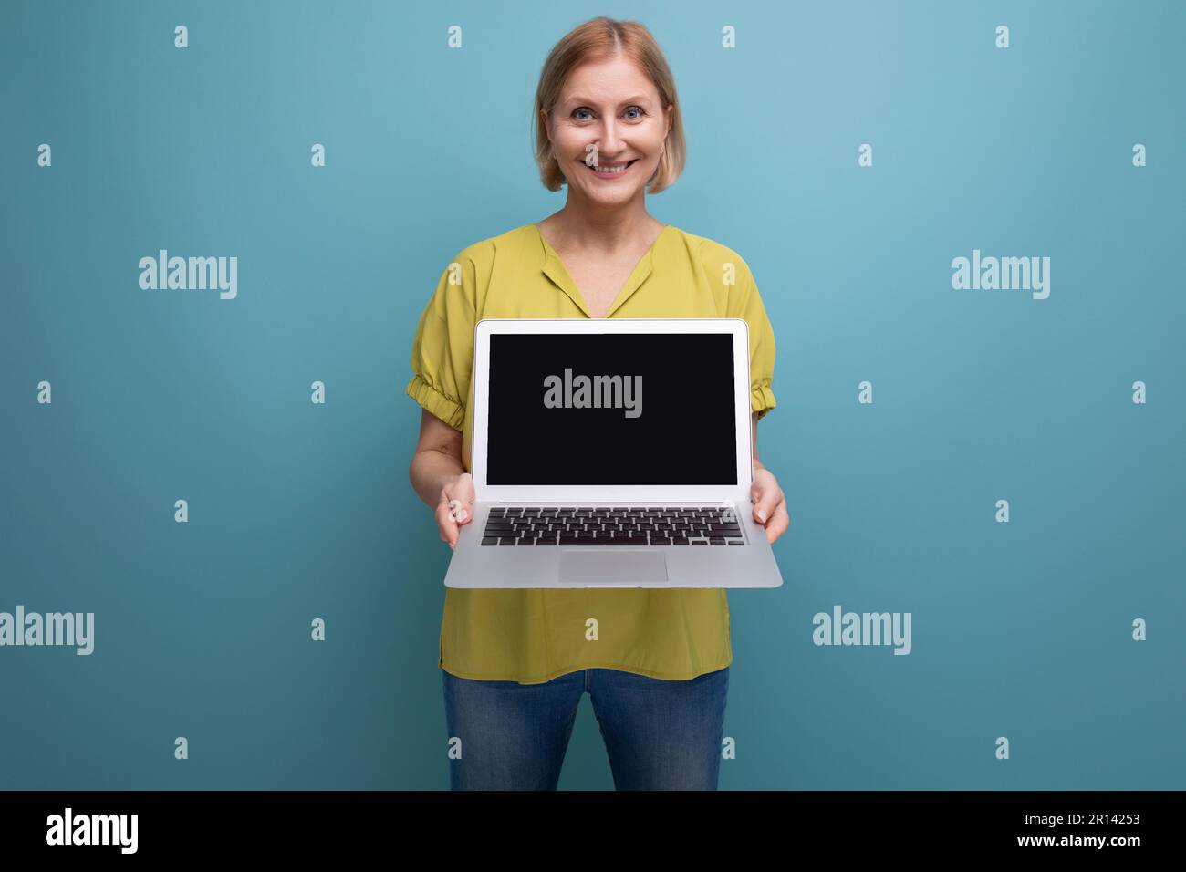 middle aged woman with laptop on studio background with copy space ...