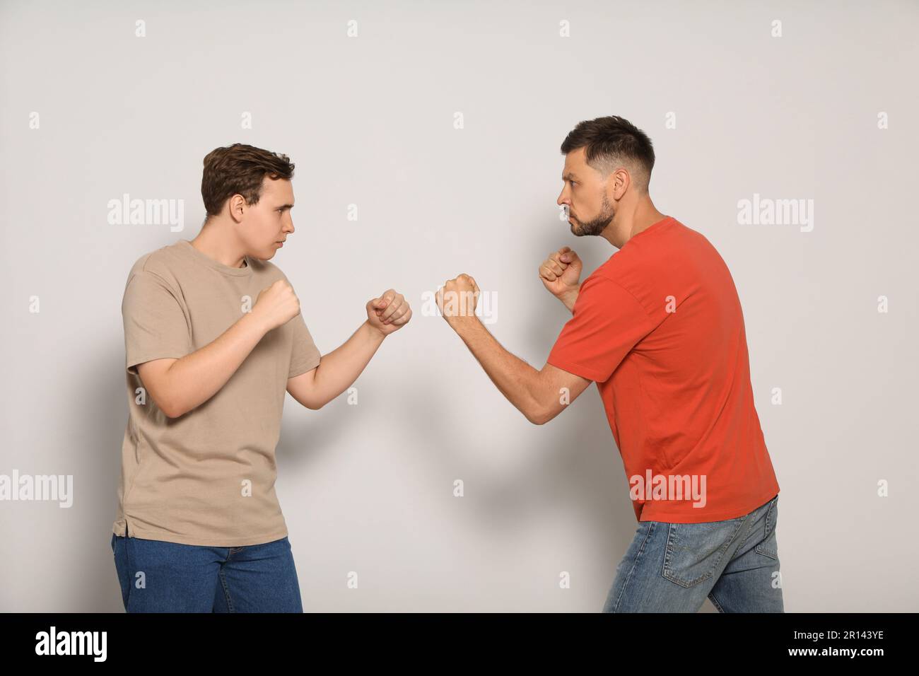 Two emotional men fighting on beige background Stock Photo - Alamy