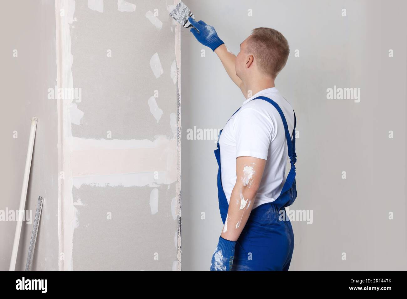 Man plastering wall with putty knife indoors. Home renovation Stock ...