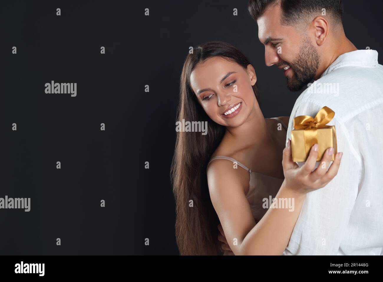 Woman presenting gift to her boyfriend on black background Stock Photo ...