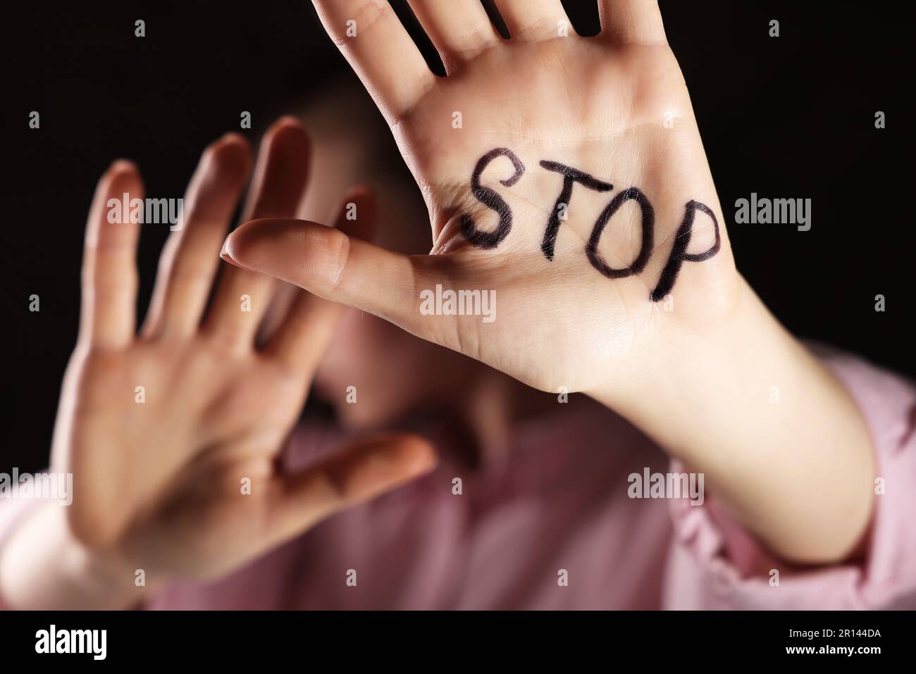 Woman with word Stop written on hand against dark background, closeup ...