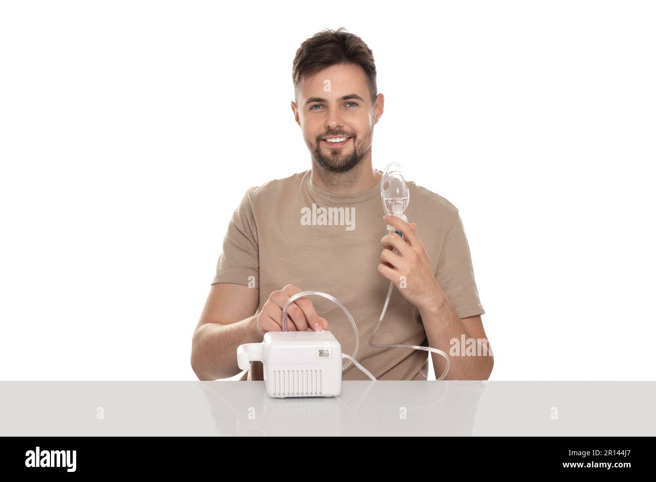 Man turning on nebulizer for inhalation at table against white ...