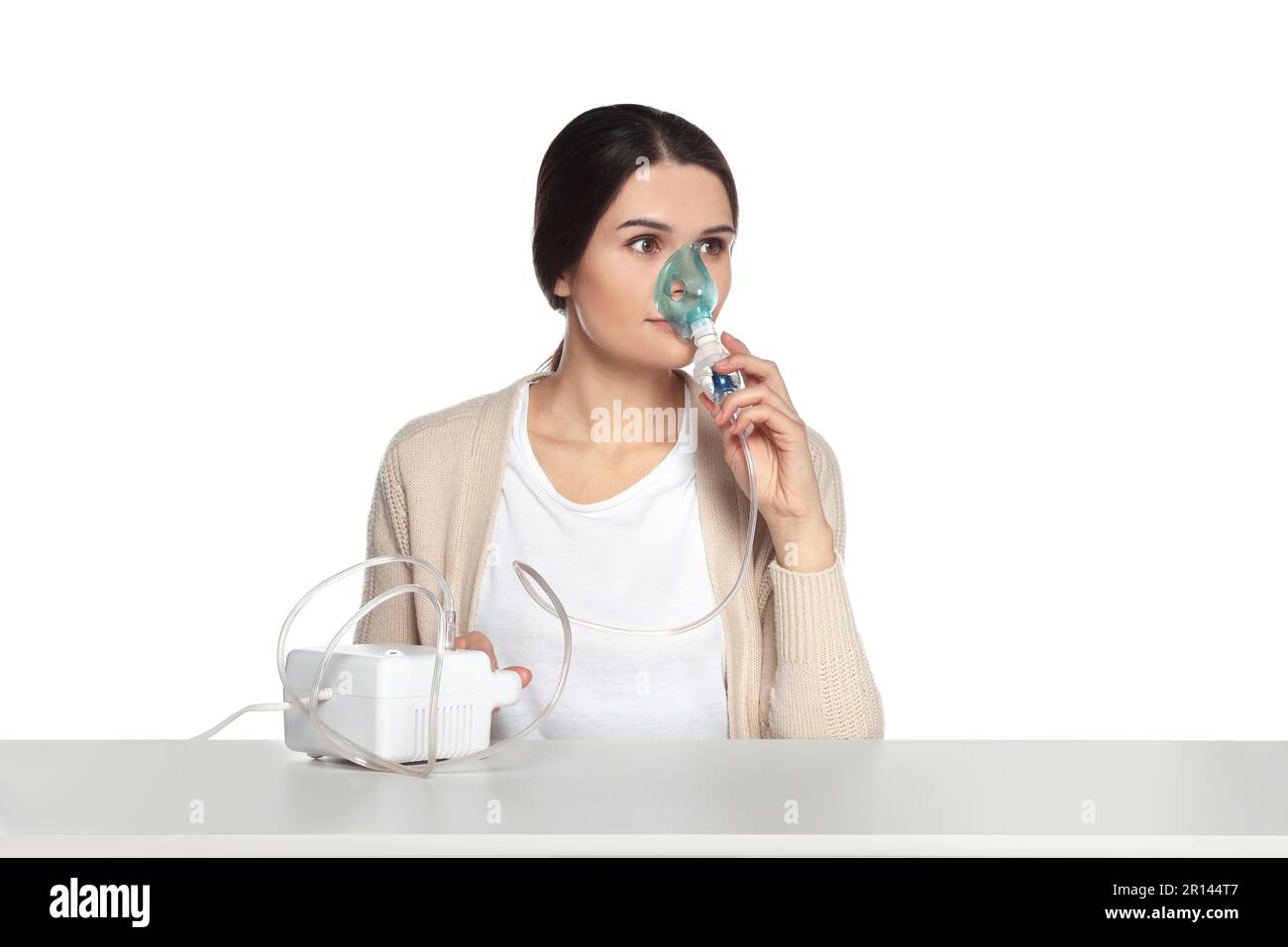 Young woman using nebulizer at table on white background Stock Photo ...