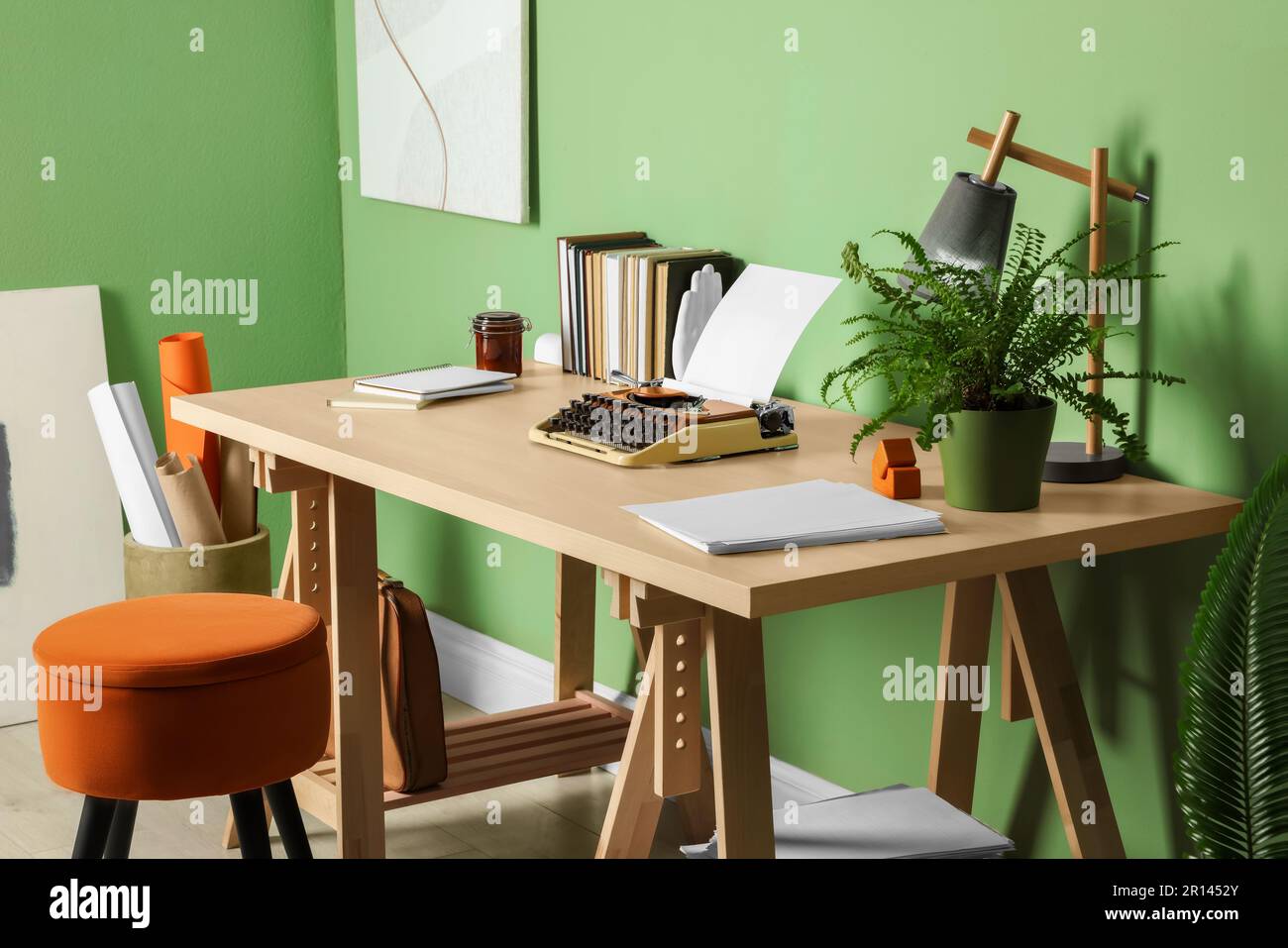 Writer's workplace with typewriter on wooden desk near pale green wall ...
