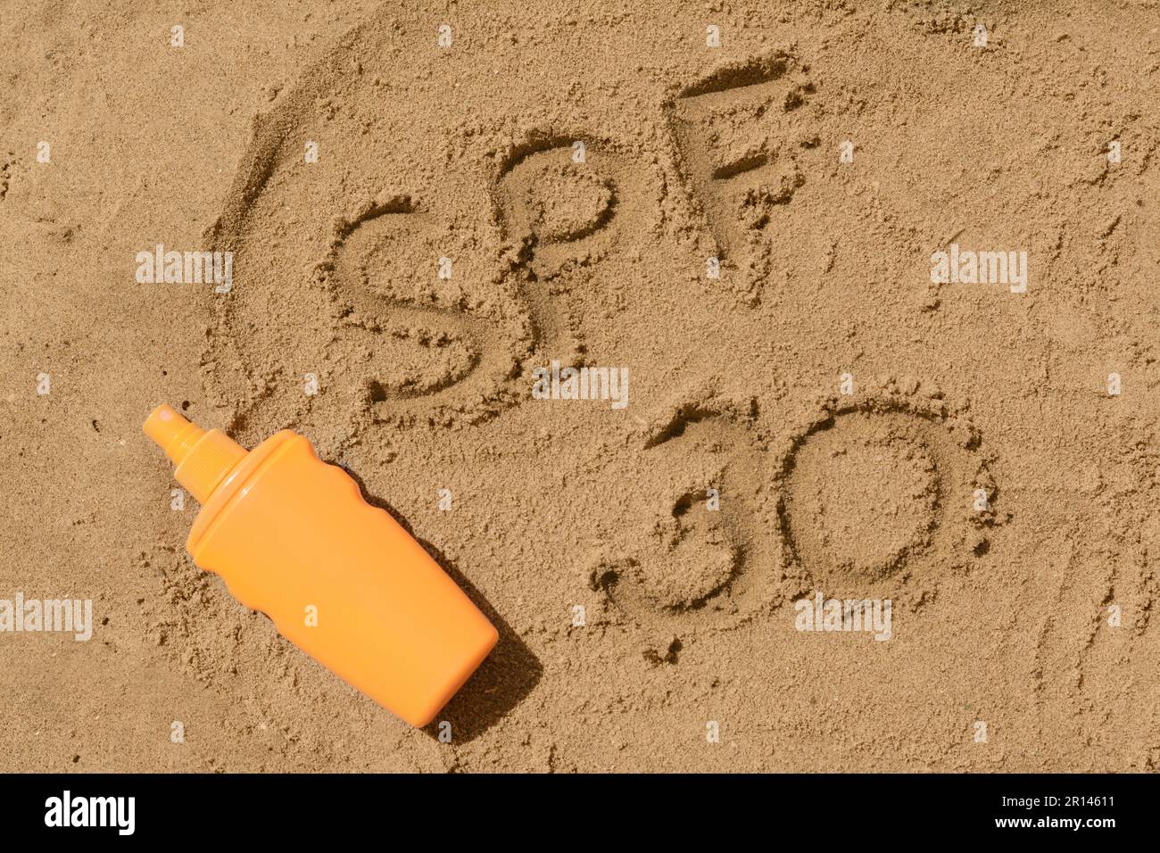 Abbreviation SPF 30 written on sand and blank bottle of sunscreen at ...