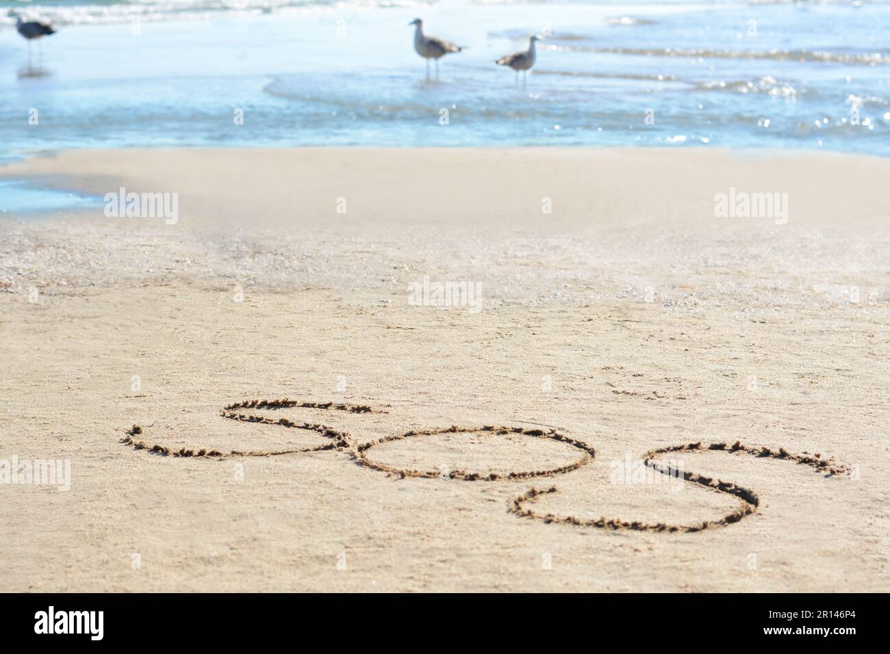 SOS message written on sand near sea Stock Photo - Alamy