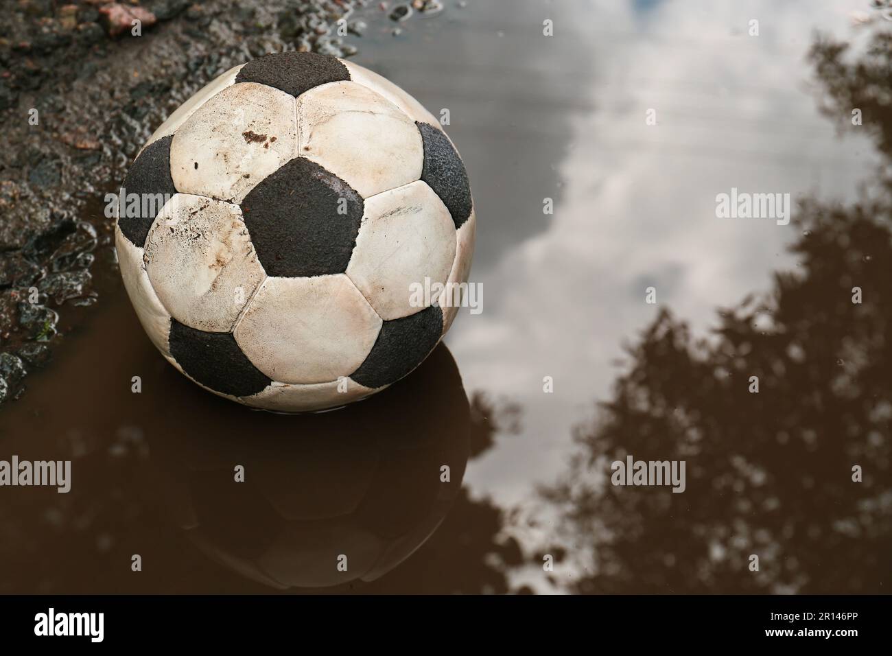 Dirty soccer ball in muddy puddle, space for text Stock Photo - Alamy