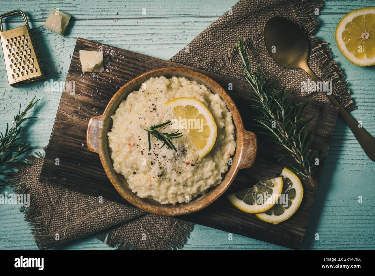 Lemon rice risotto with rosemary and fresh lemon slices on light green ...