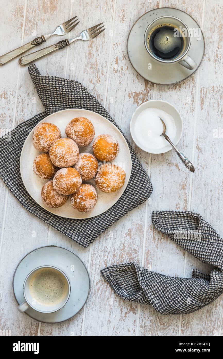 Fried curd balls with sugar and two cups of coffee on white wooden ...