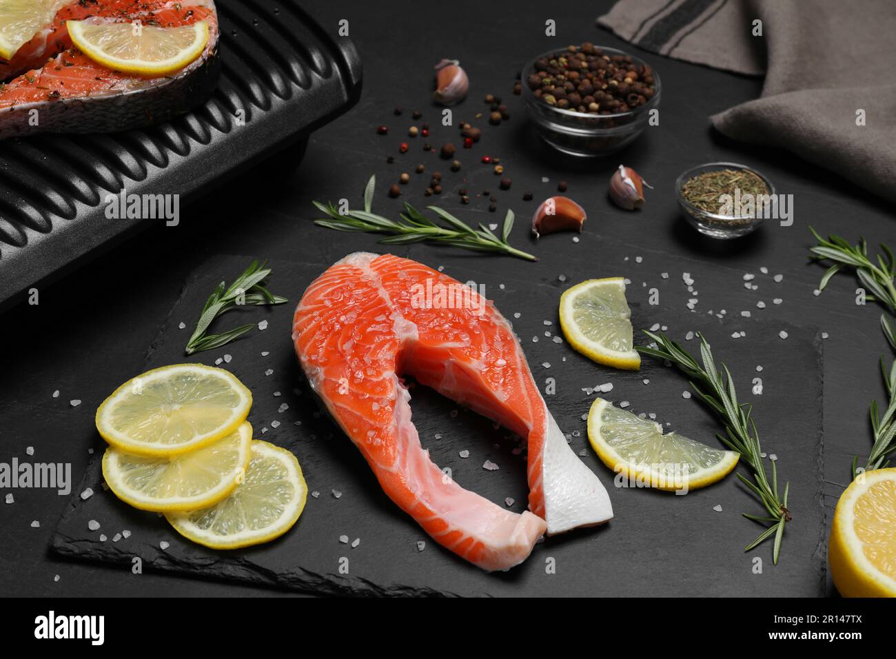 Cooking salmon. Grill, fresh fish steaks, lemon and spices on dark ...