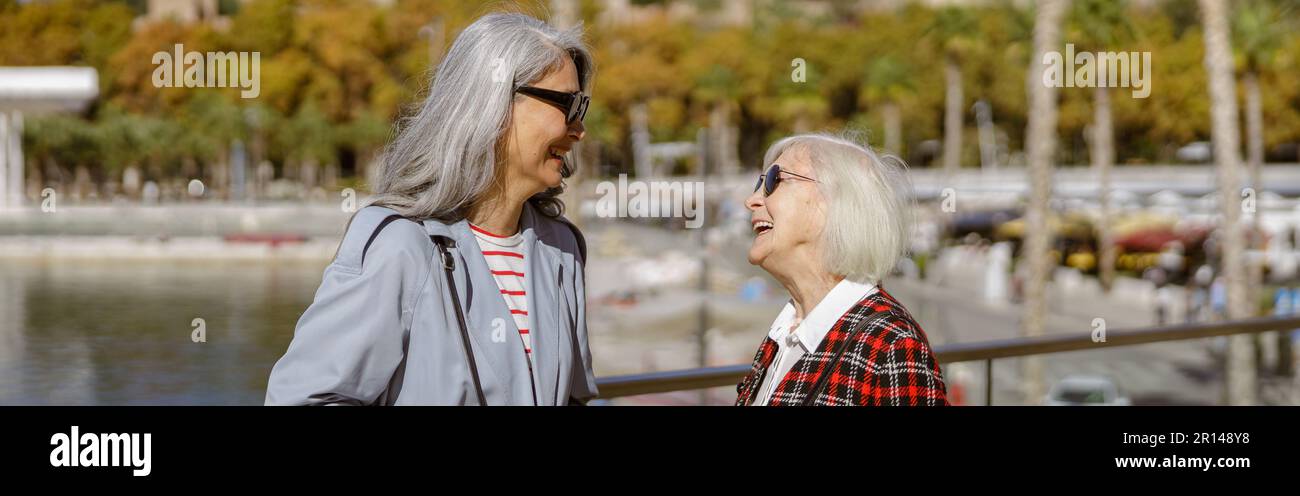 Female friends having conversation on promenade by sea Stock Photo - Alamy