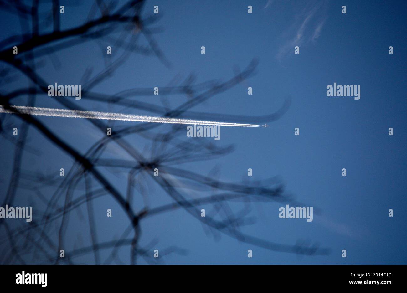 A commercial jet airplane leaves a contrail as it flies high over ...