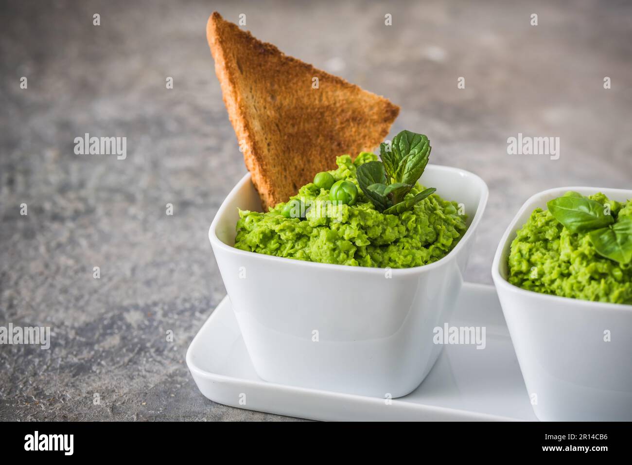 Pea puree with basil, mint and roasted bread on rustic gray background ...