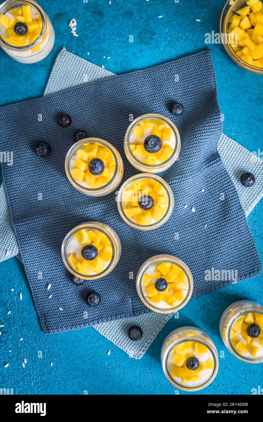 Coconut rice pudding with mango in dessert glasses on blue background ...