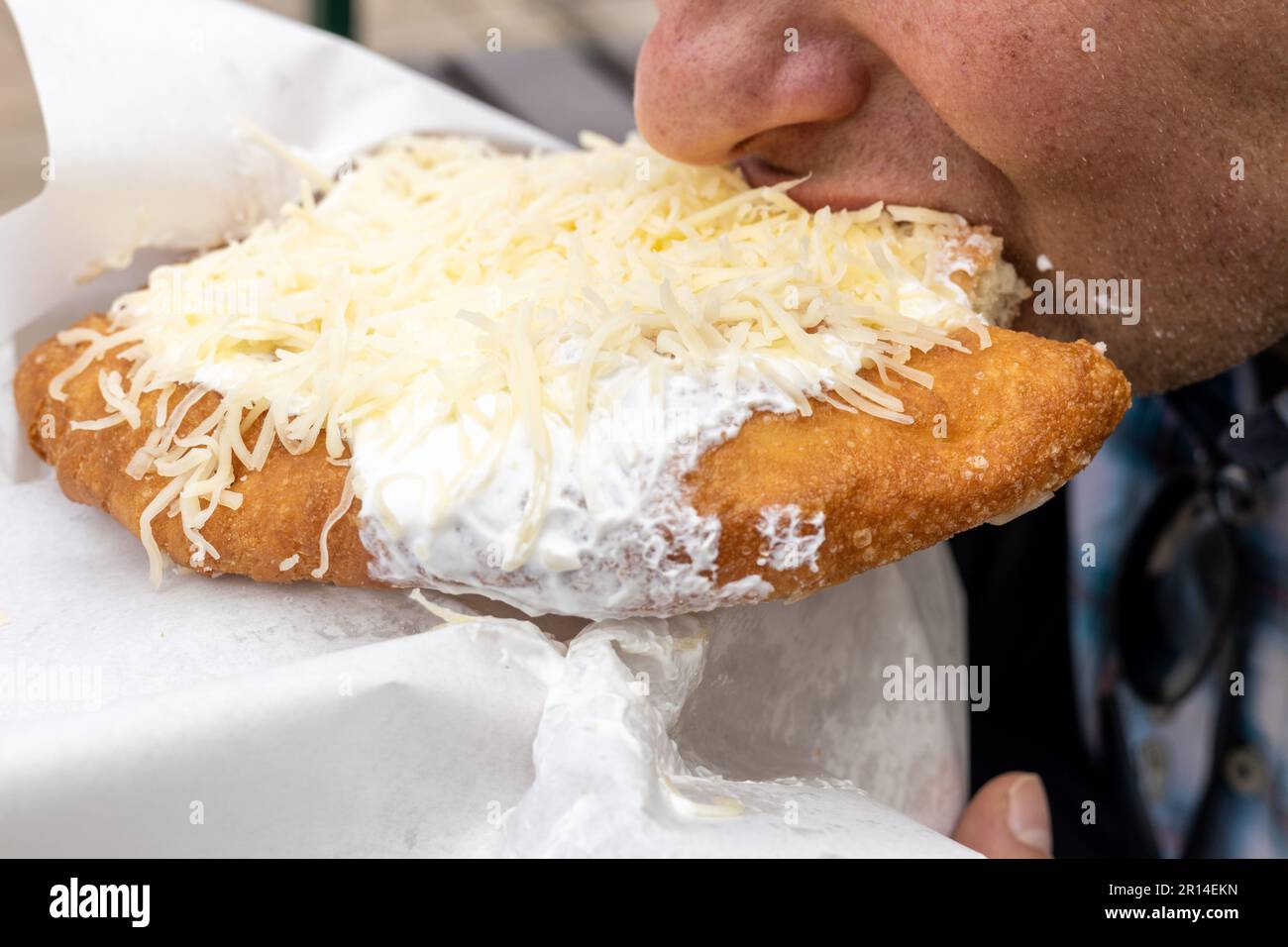 A man eating a traditional langosh, a deep-fried pastry popular in ...