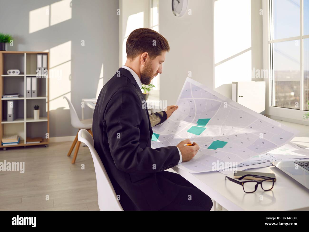 Professional cartographer working with printed cadastral map at table ...