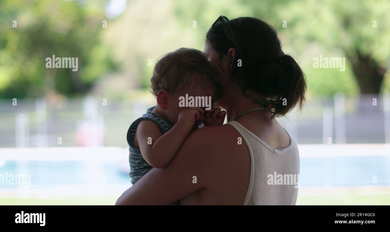 Silhouette of mother holding baby infant outside, authentic casual and ...