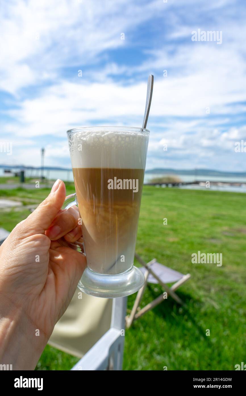 drinking latte macchiato caffee at lake Balaton in Hungary on the beach ...