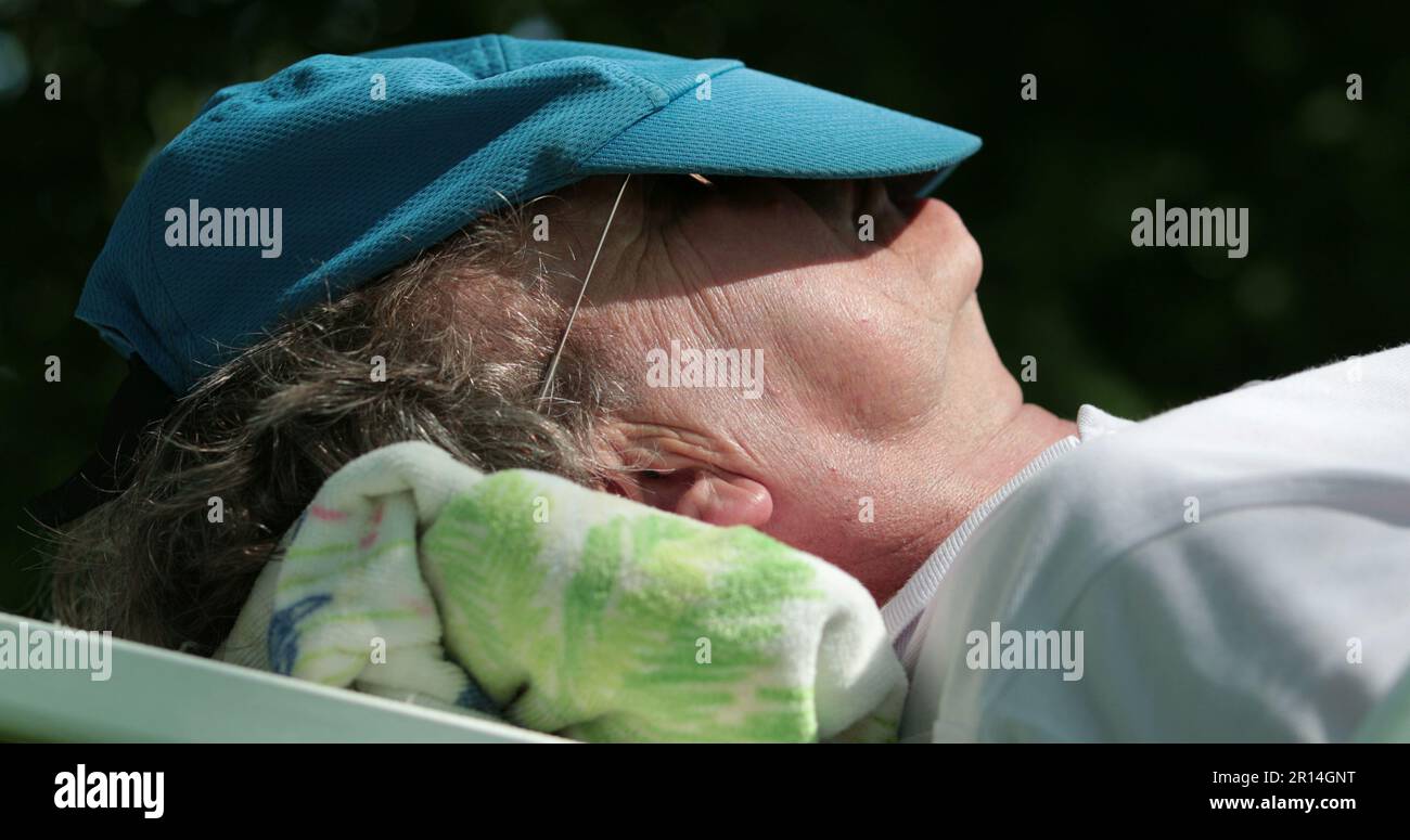 Senior man ennjoying summer day afternoon nap, face covered with hat ...
