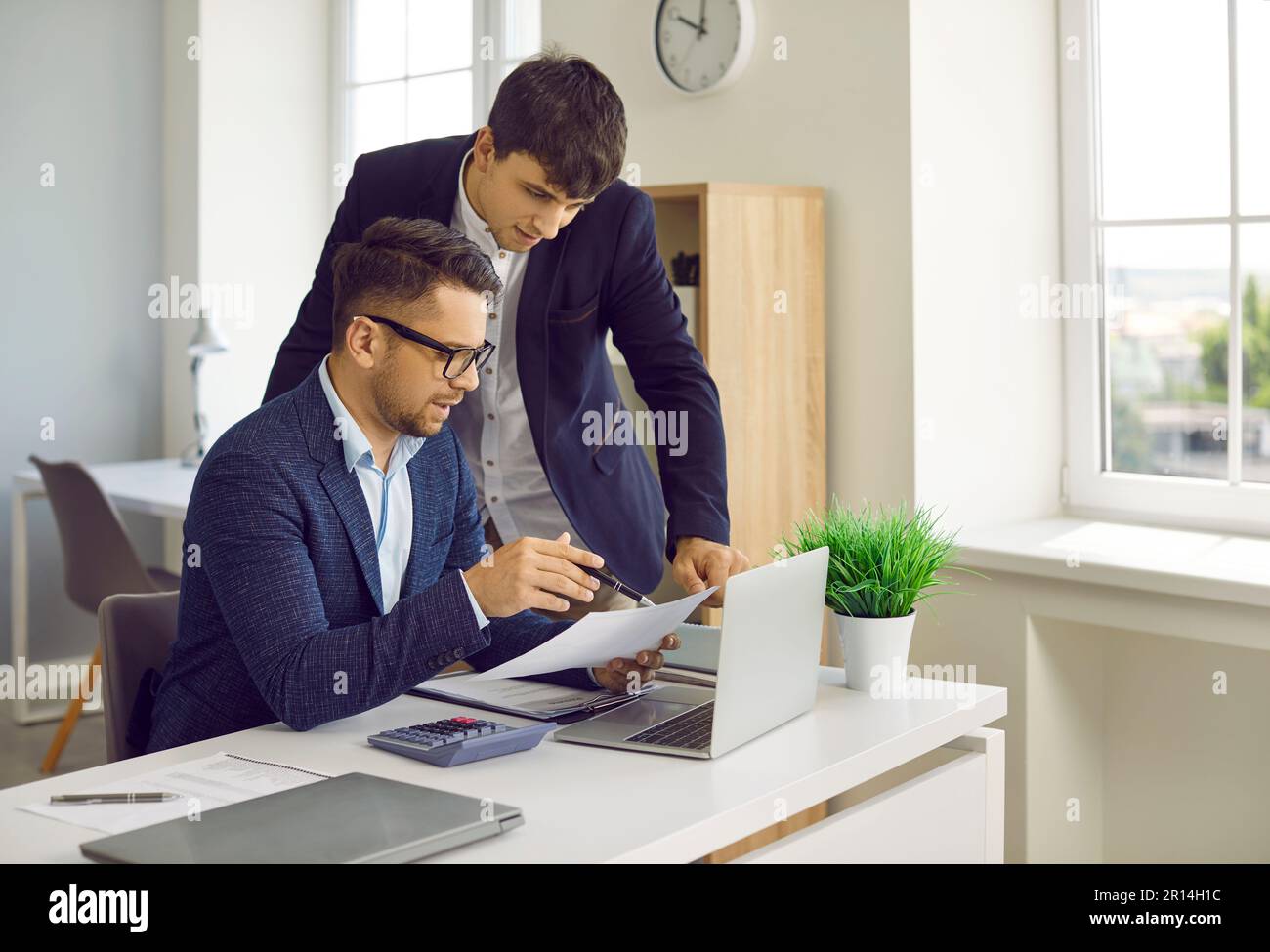 Male financial director giving directions to his assistant while ...