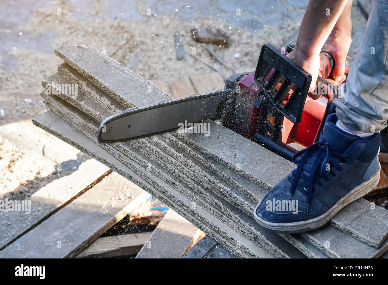 Cutting old wooden chipboards with electric chainsaw, splinters flying ...