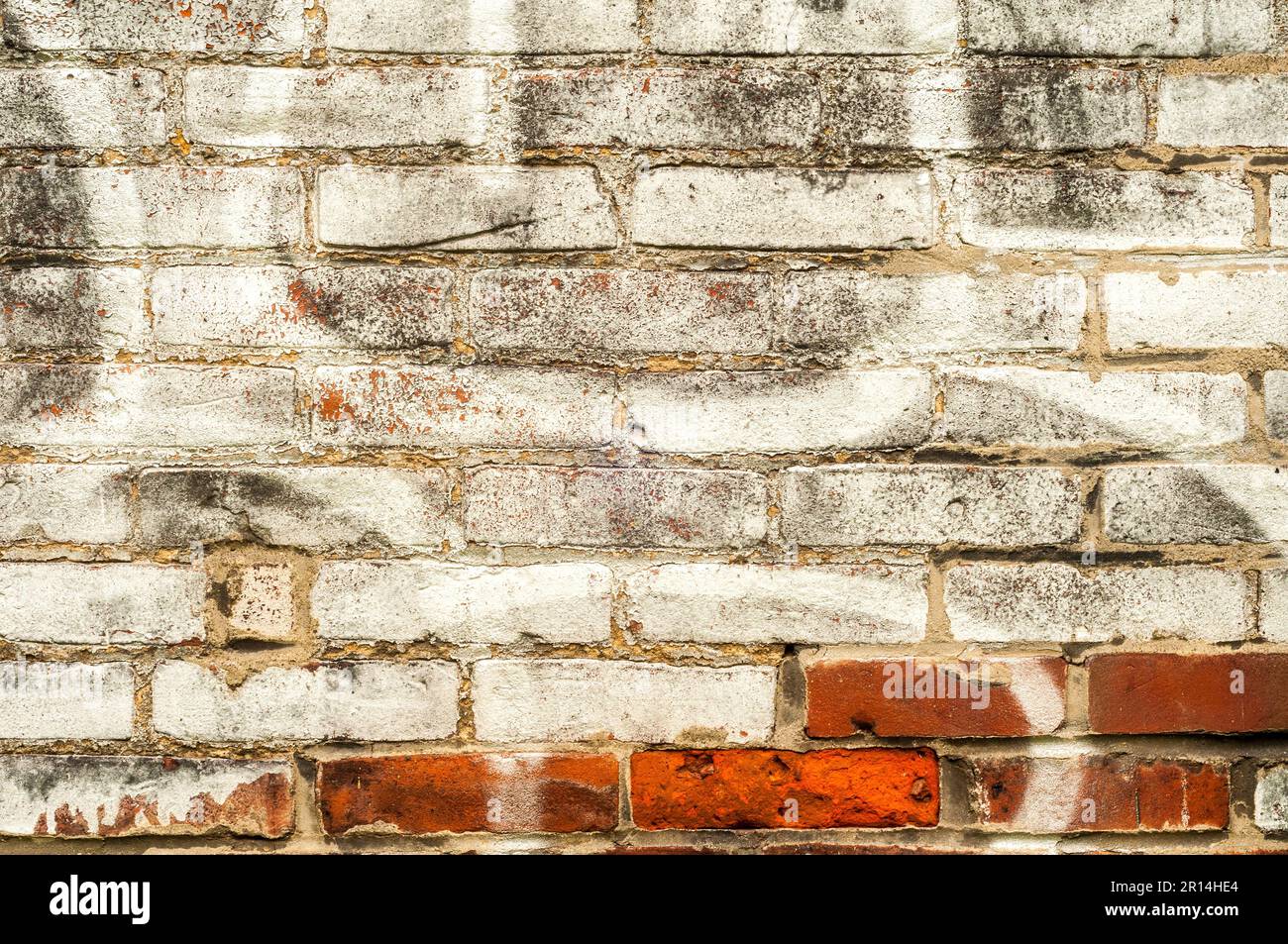 A partially white-washed brick wall with graffiti swirls forms an ...