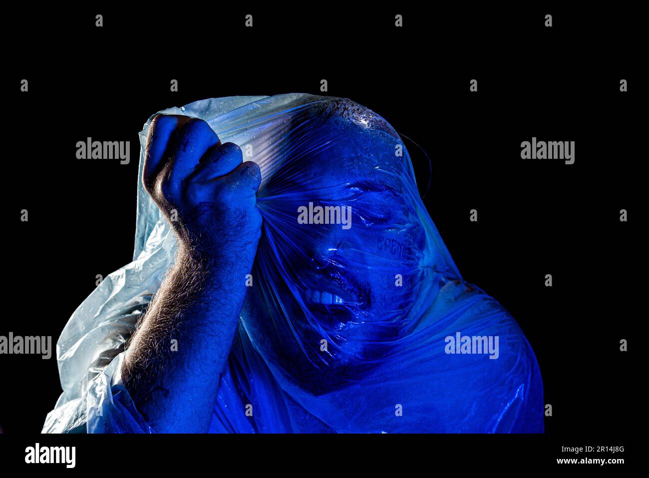 Man with plastic bag over his head, suffocated. Studio shot with blue ...