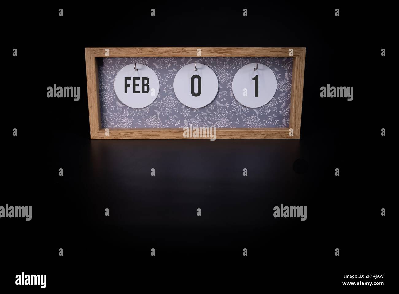 A wooden calendar block showing the date February 1st on a dark black ...