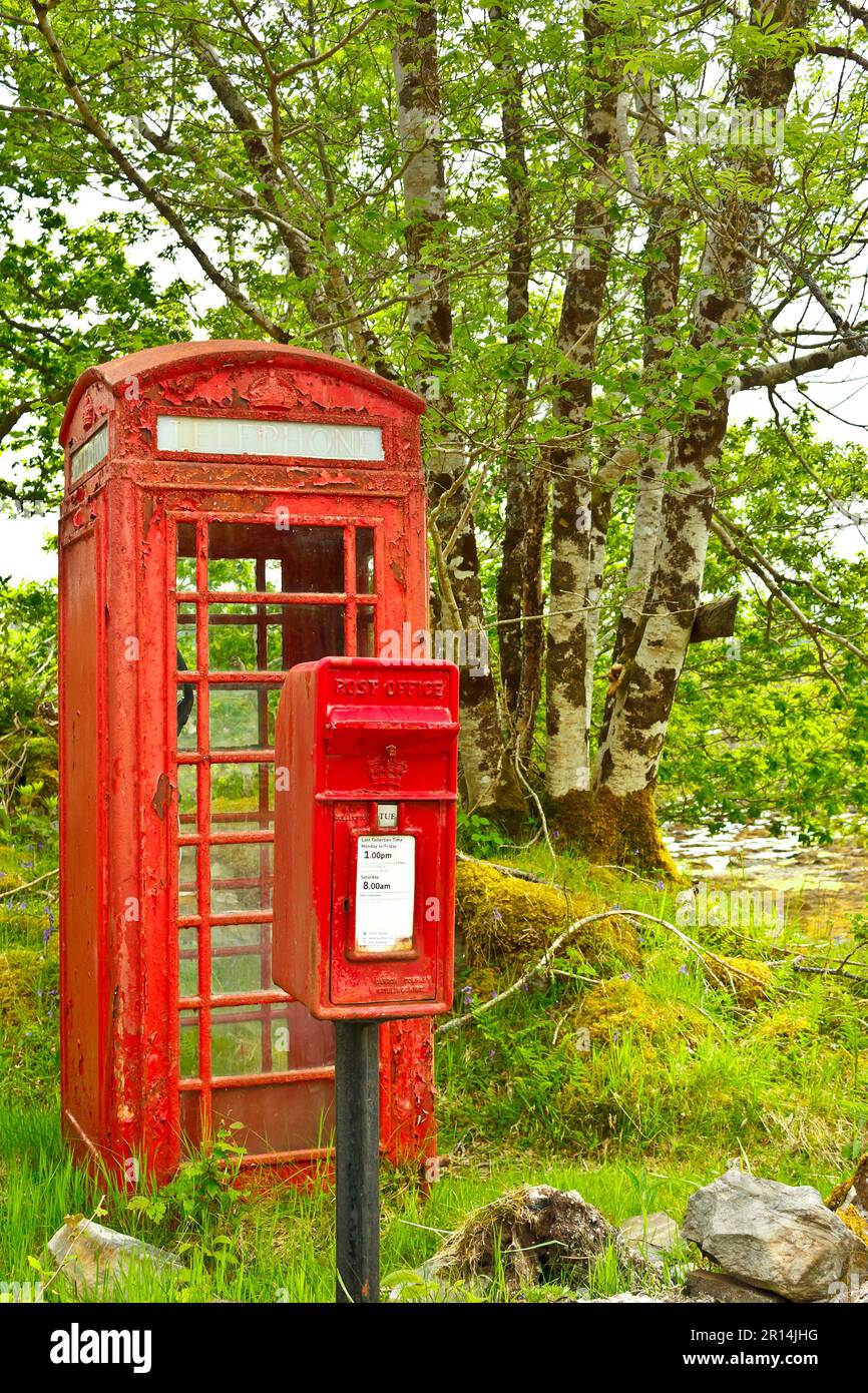 Old and rusted red telephone booth and post box on a pole at the coast ...