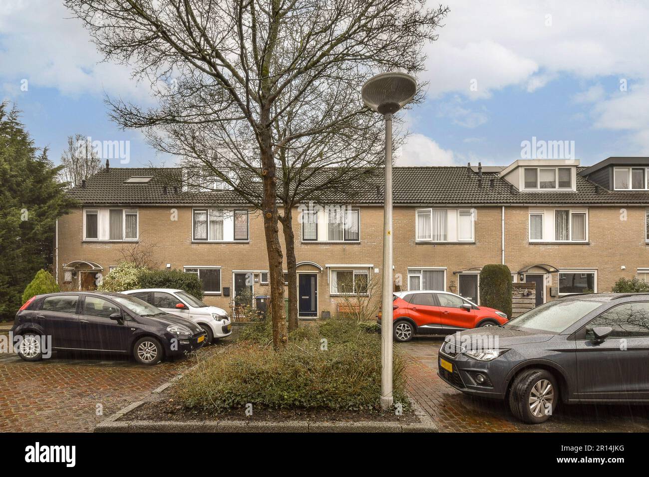 two cars parked in front of a house with a street light attached to the ...