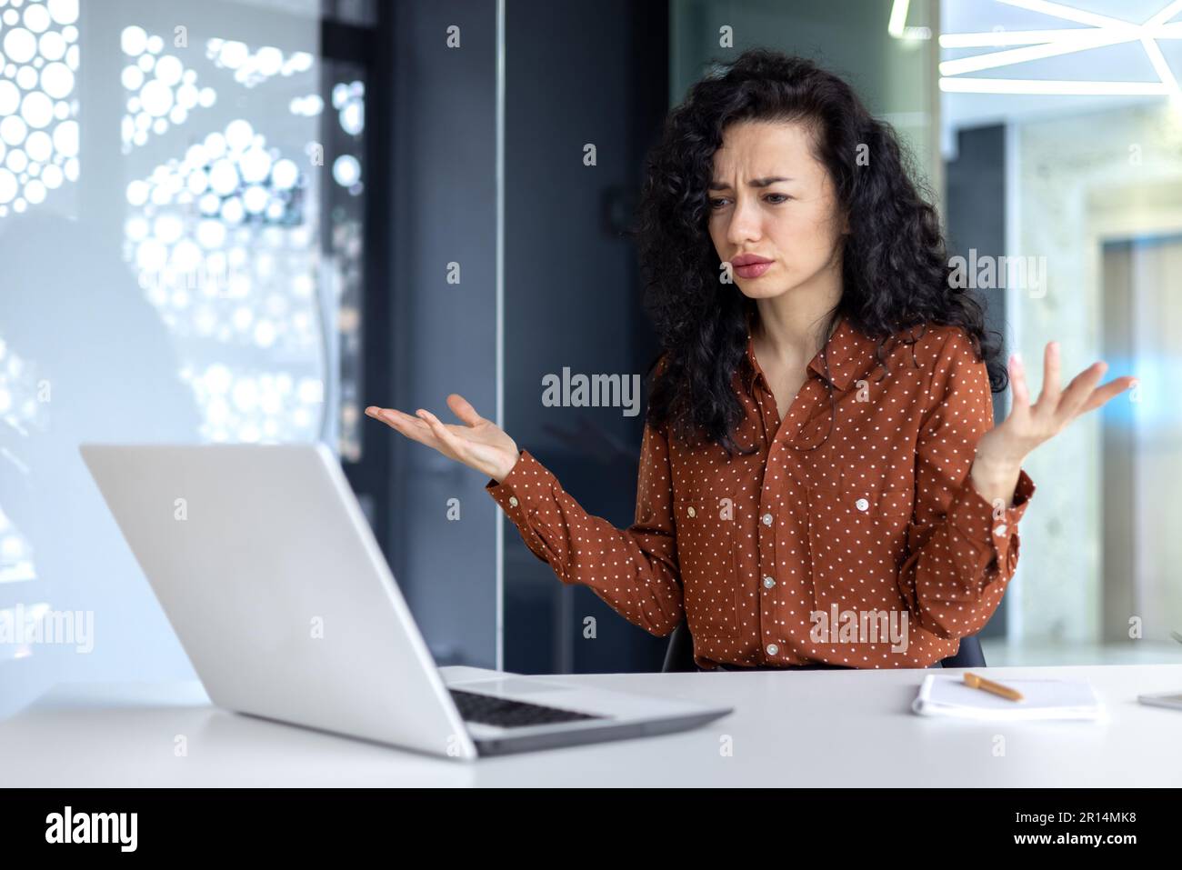Frustrated business woman looking at laptop screen, dissatisfied female worker spreading hands ...
