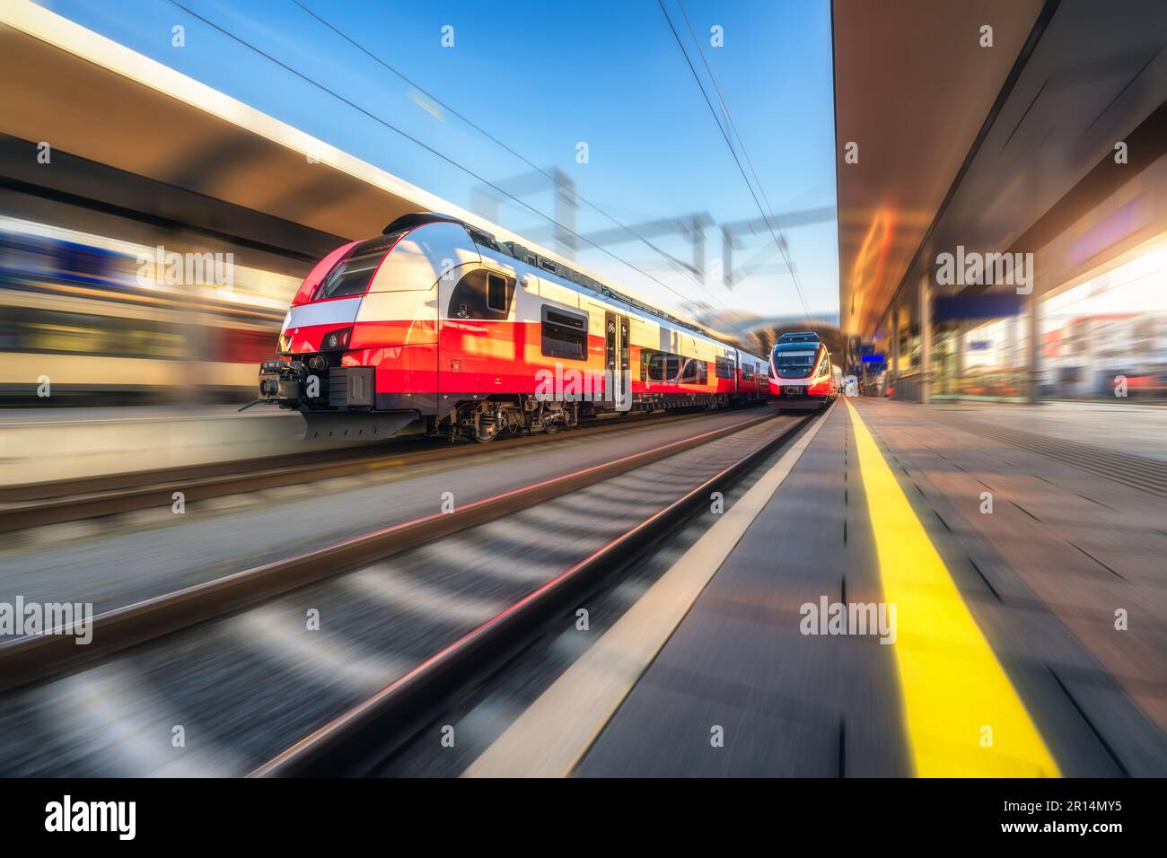 Orange high speed train in motion on the railway station Stock Photo ...