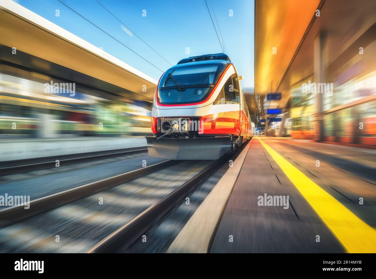Orange high speed train in motion on the railway station Stock Photo ...