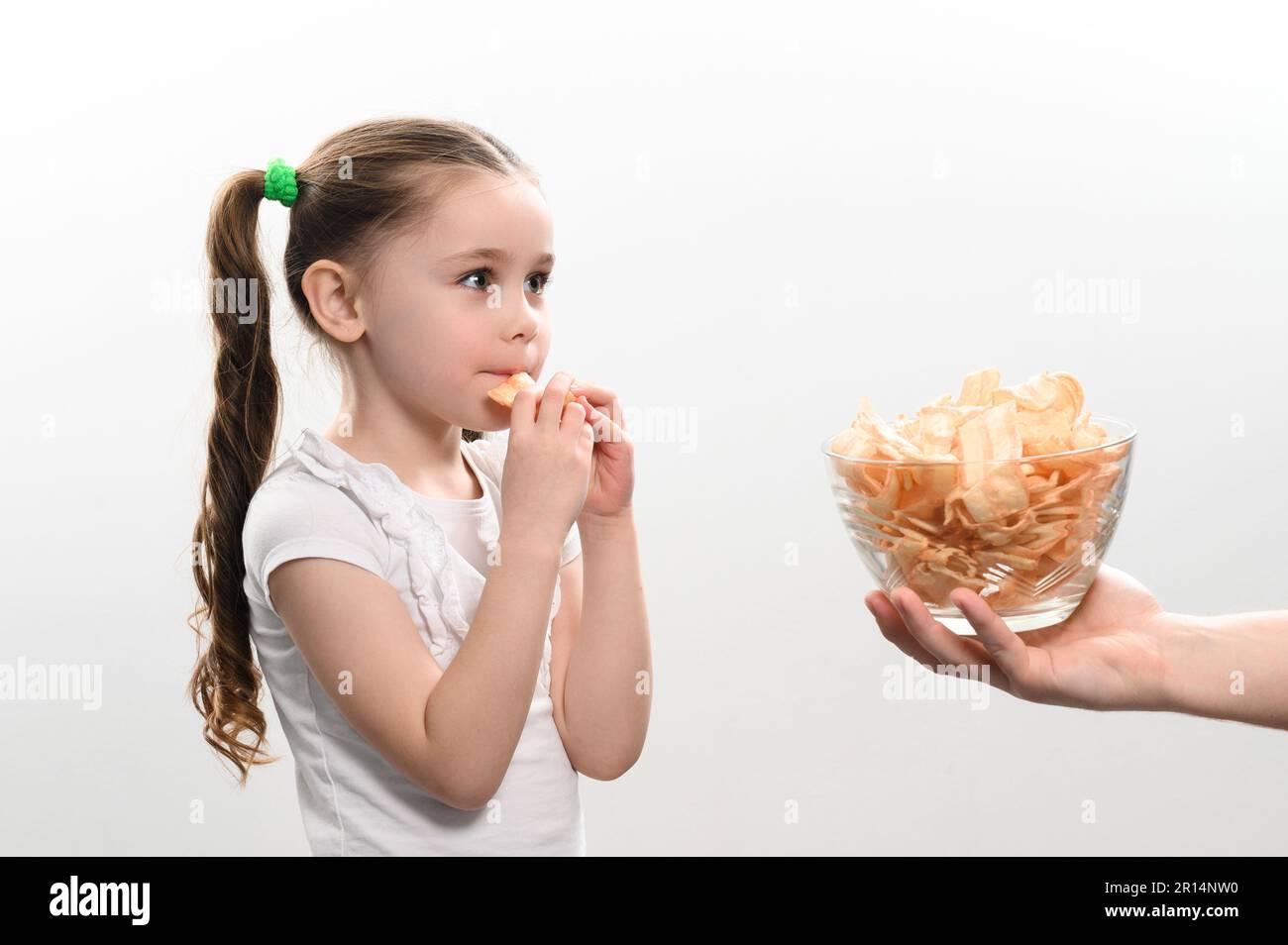 Little girl is given a big bowl of chips snacks with lard, white ...