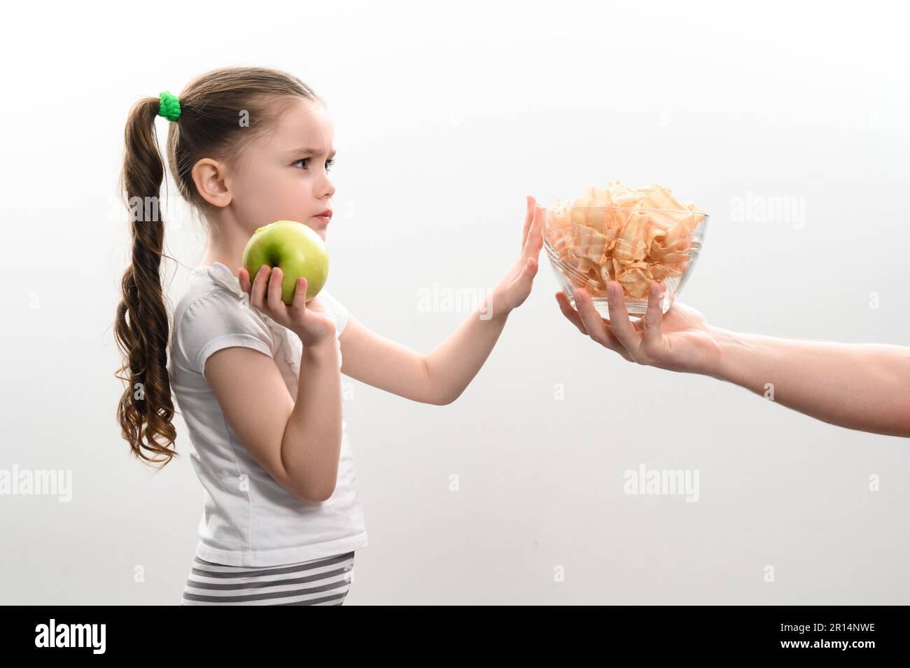 Big bowl of chips and fruit, beautiful little girl eats an apple, child ...