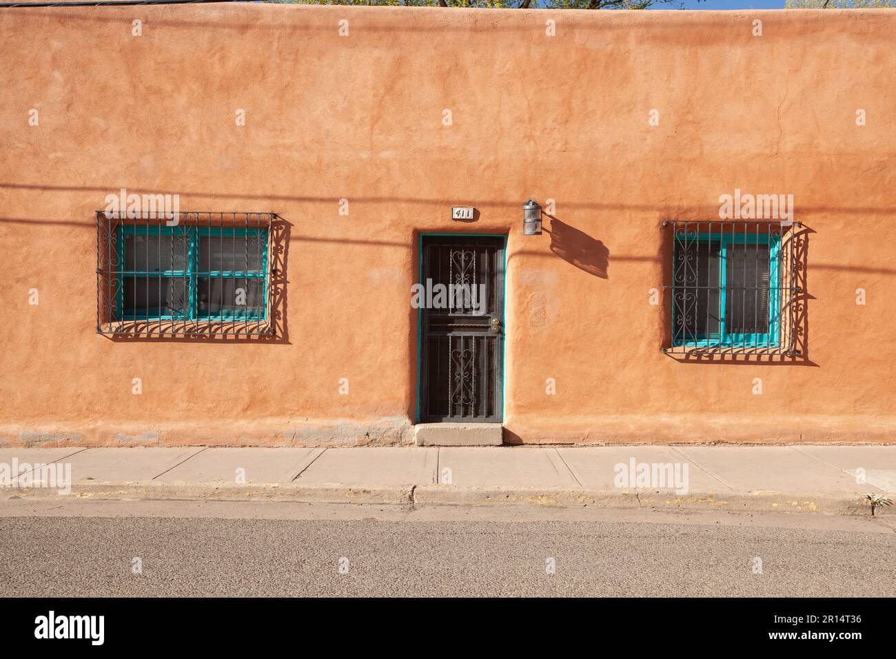 An exterior view of an old adobe building with turquoise colored window ...