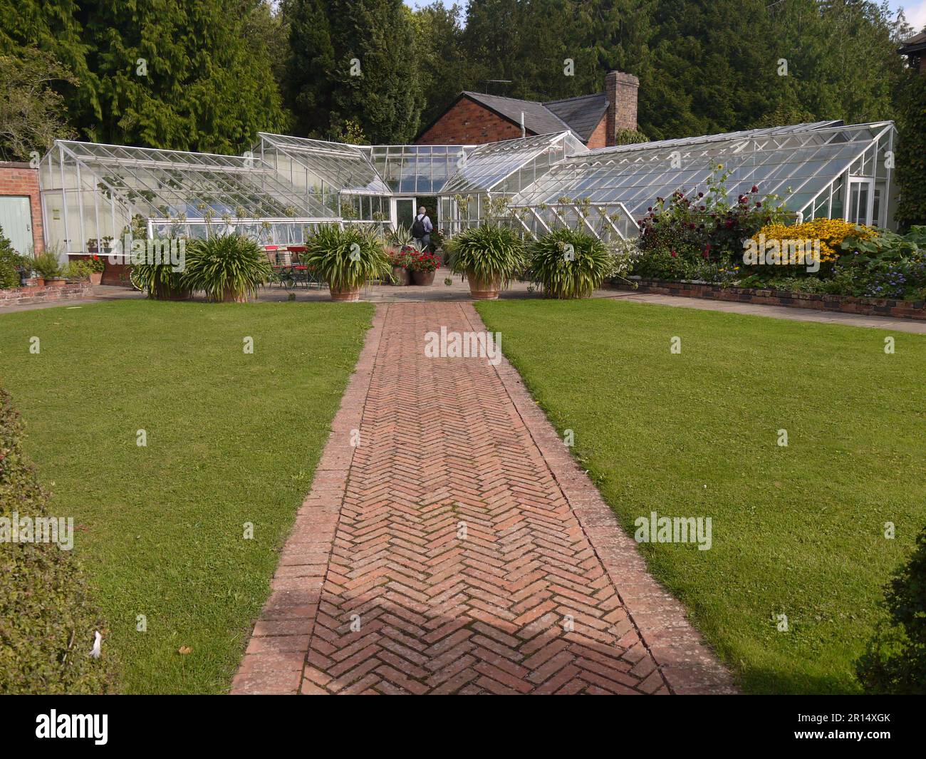 A herringbone brick path leads to the glasshouses in the corner of the ...
