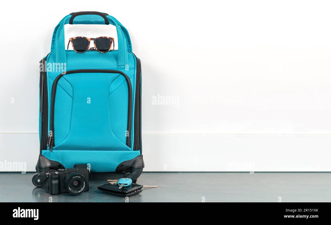 Travel bag with sunglasses, camera, wallet, and keys against a white ...
