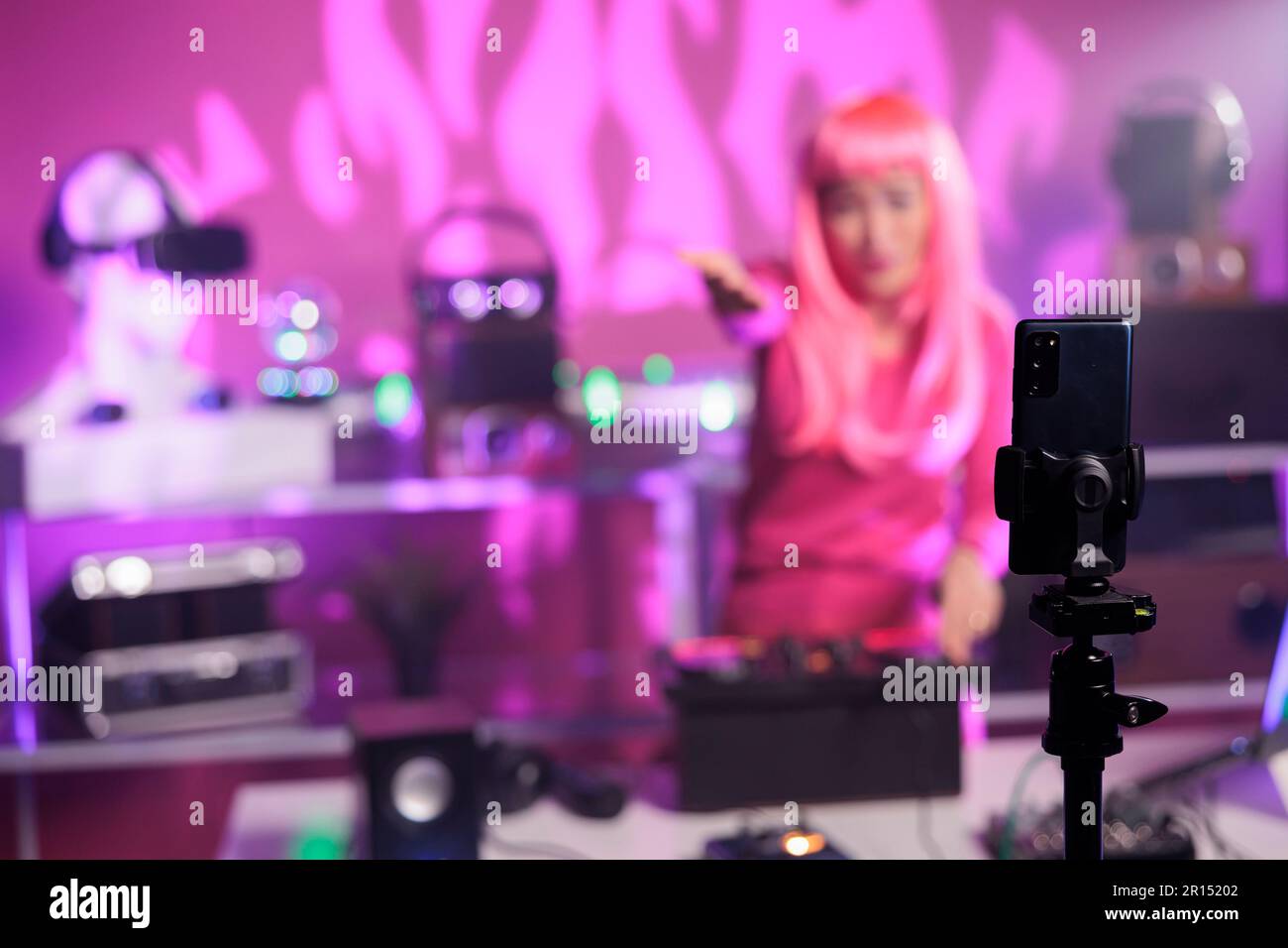 Asian dj with pink hair performing techno music using professional ...