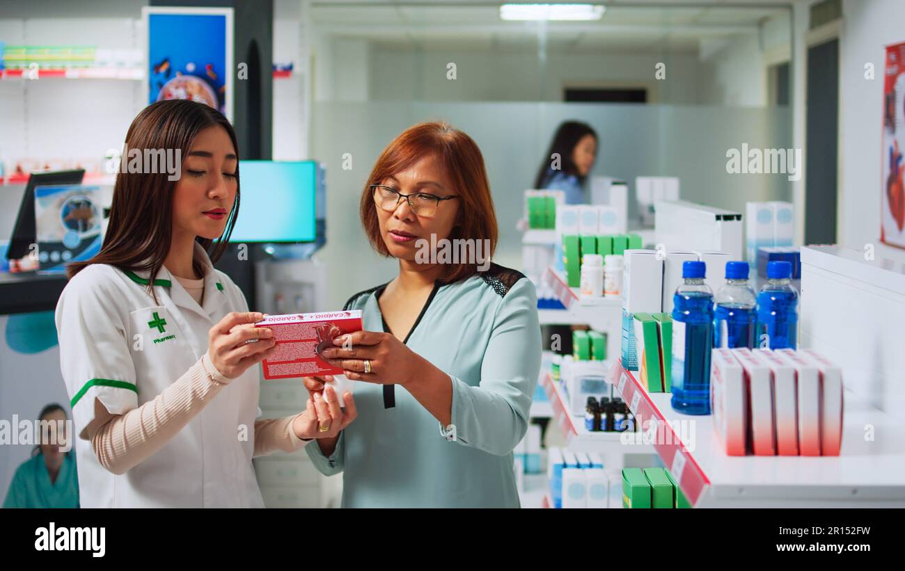 Asian people analyzing cardiology medicine with customer, pharmacist ...