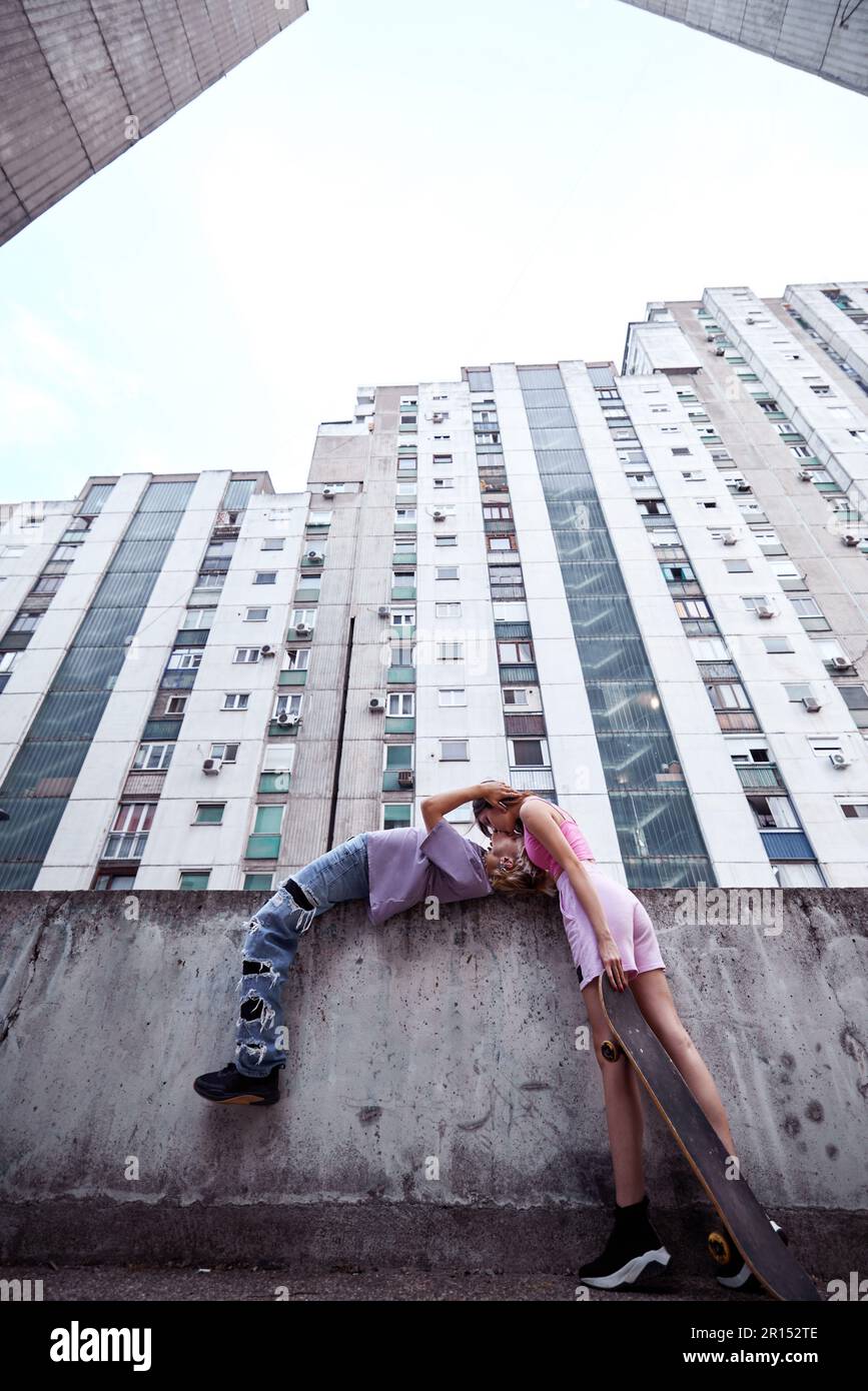 Teenage couple kissing and hugging in urban exterior surrounded by ...