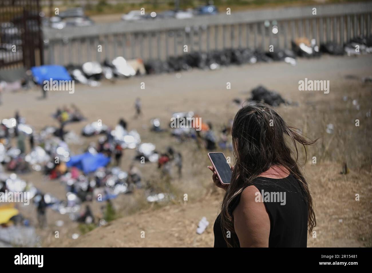 Tijuana, Mexico. 11th May, 2023. A migrant calls a food and drink delivery services on her ...