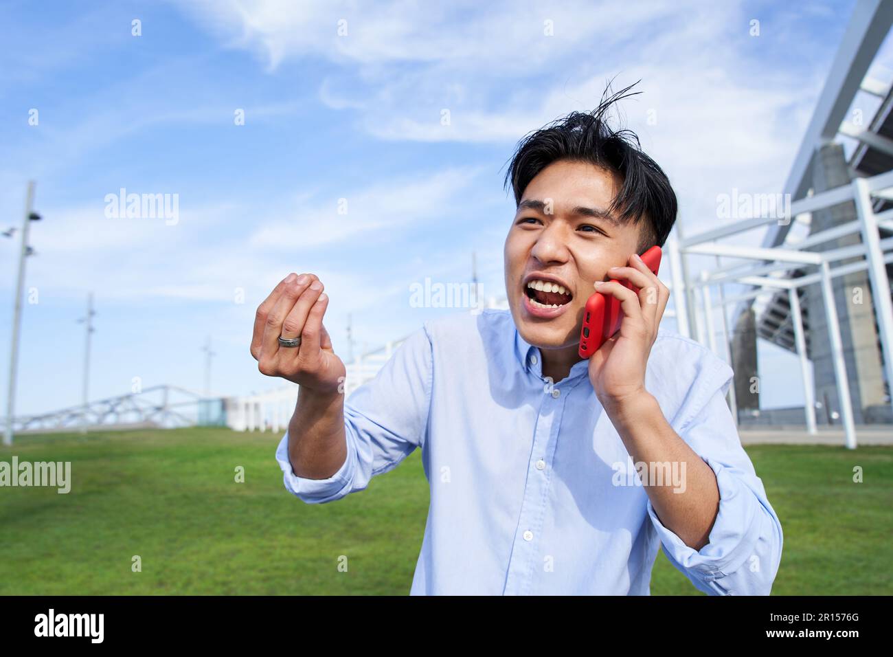 Angry young Asian man talking on cell phone. Annoyed Chinese boy argues ...